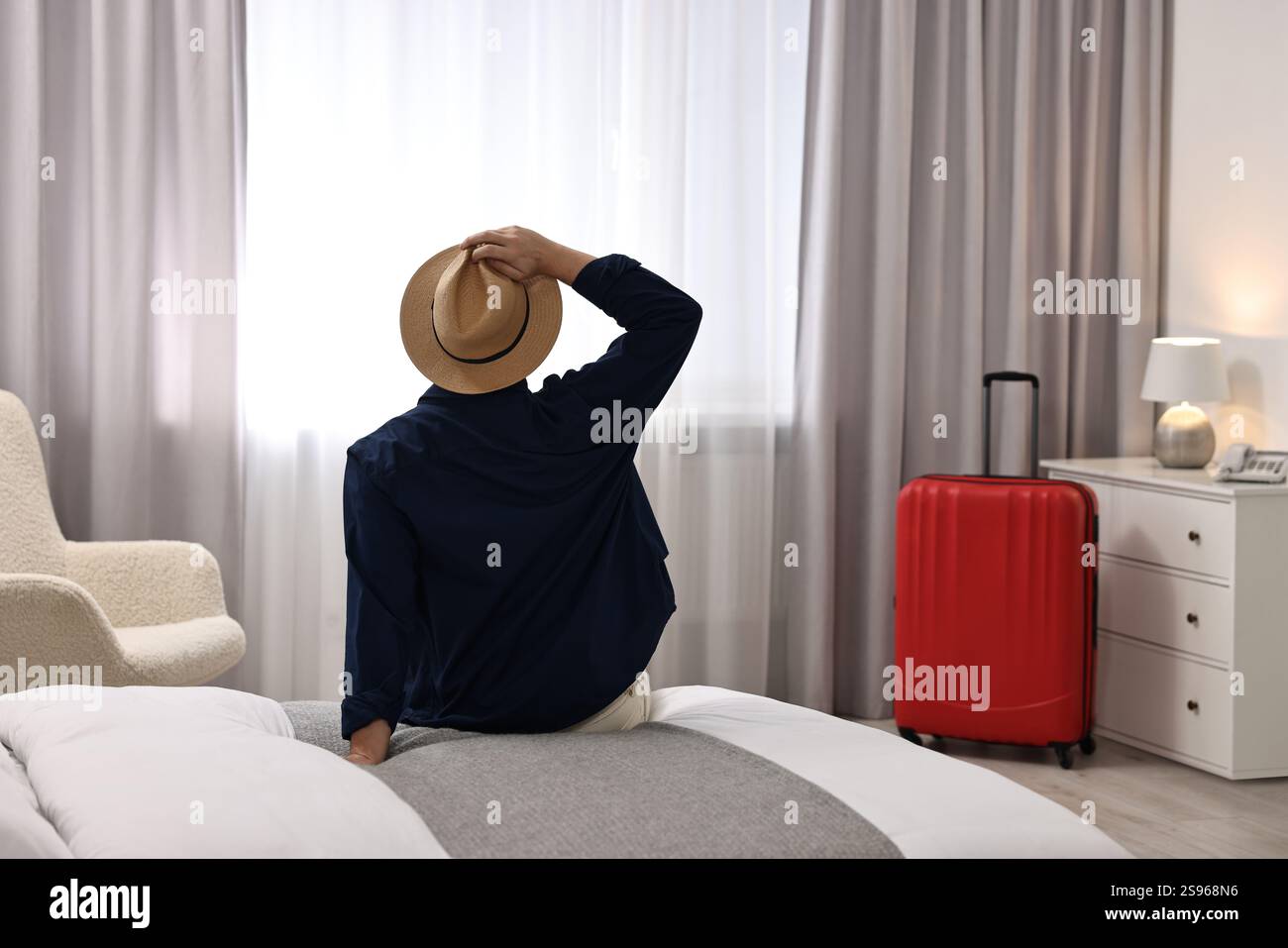 Traveller sitting on bed in hotel room, back view Stock Photo - Alamy