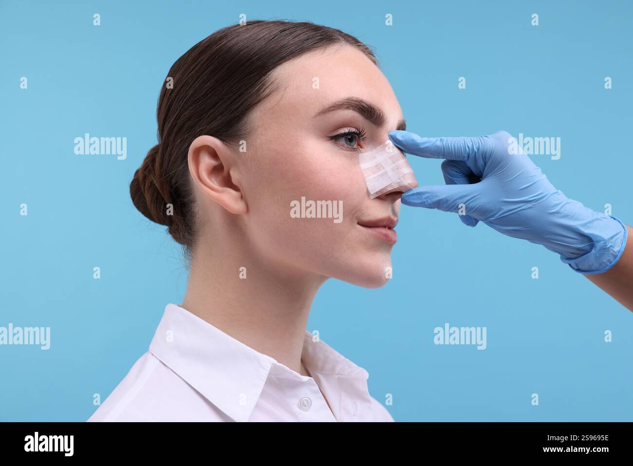 Doctor checking patient's nose after plastic surgery operation on light ...