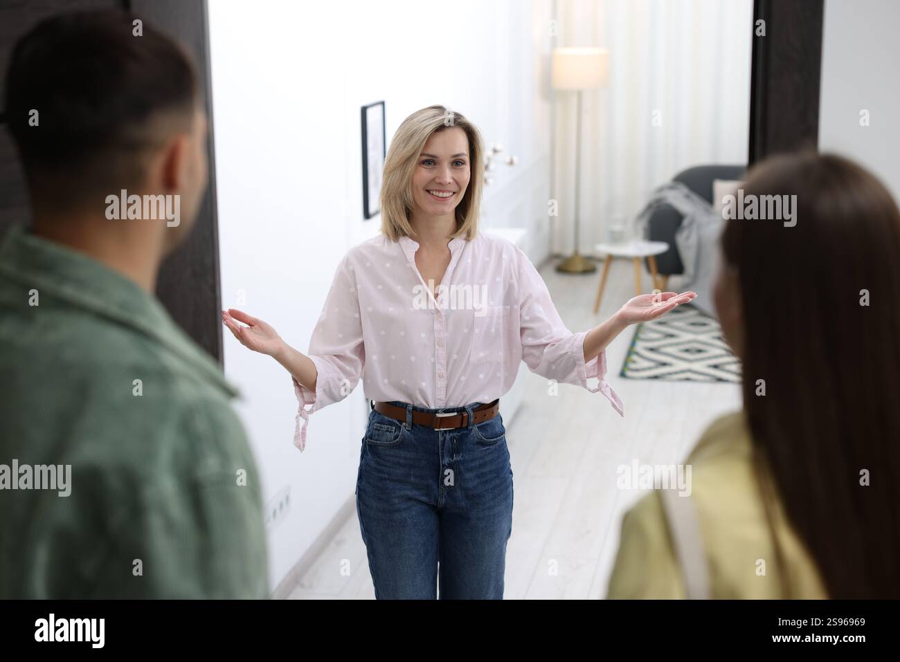 Happy woman welcoming friends to her apartment Stock Photo - Alamy