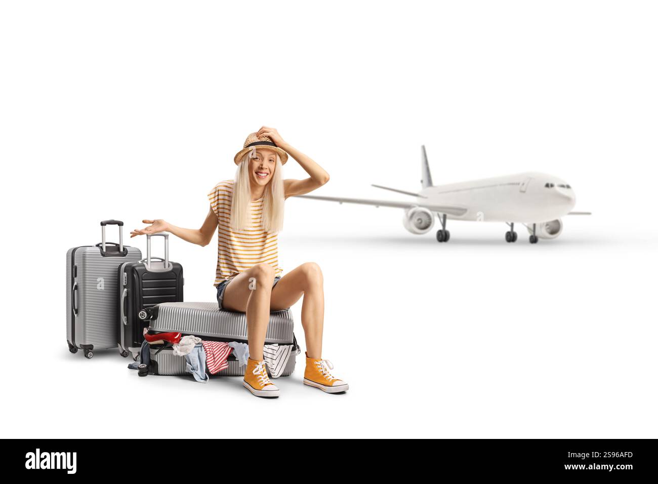 Young woman sitting on overpacked suitcases in front of a plane ...