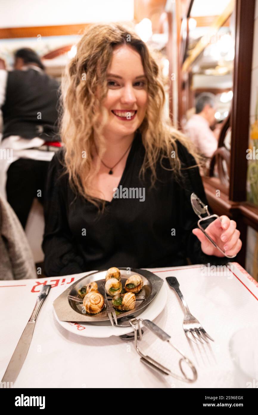 Blond woman eating escargo snails while dining at Bouillon Chartier, an ...