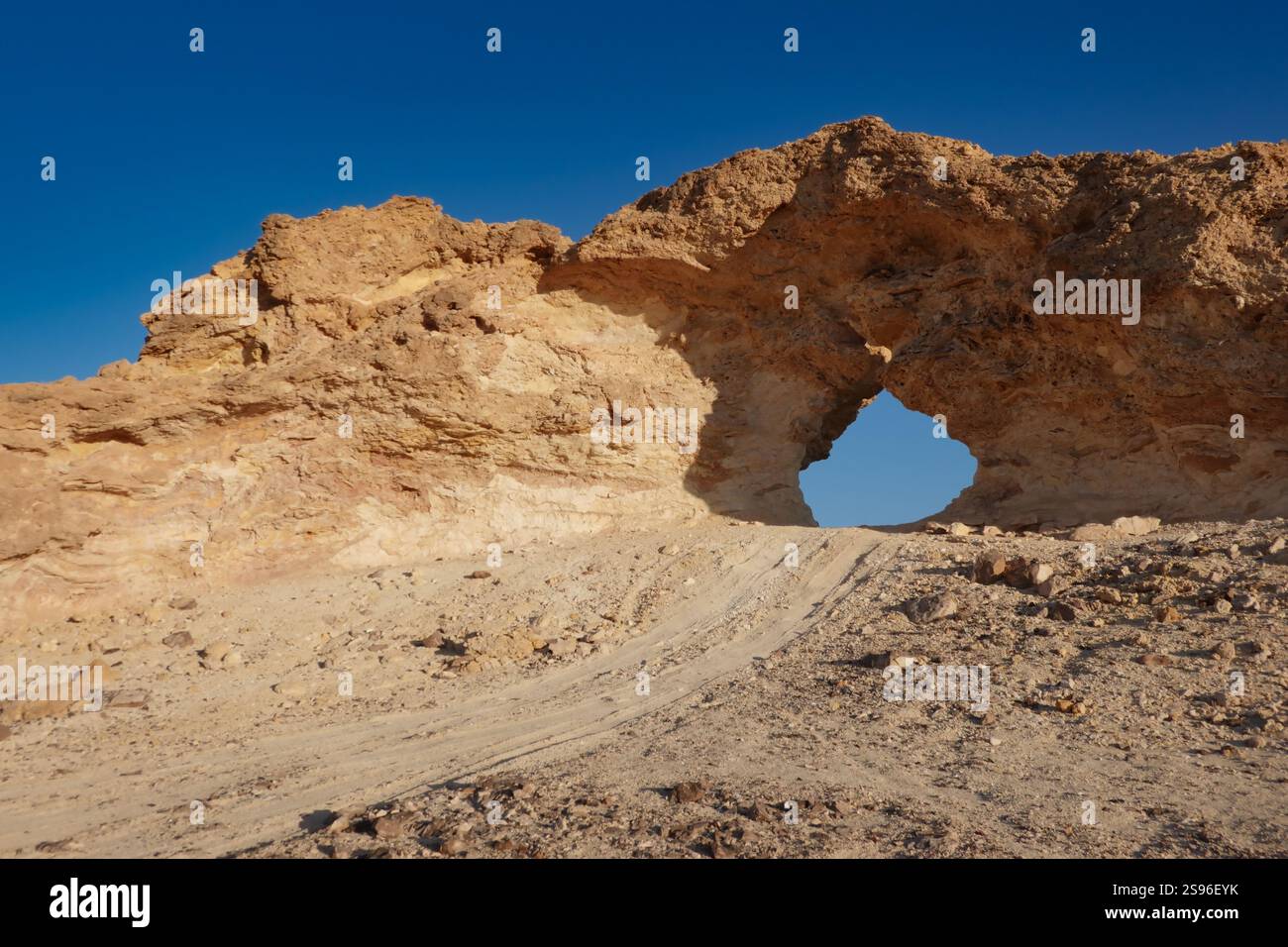 Limestone arch rock with a hole in it with tyre tracks in the sand ...