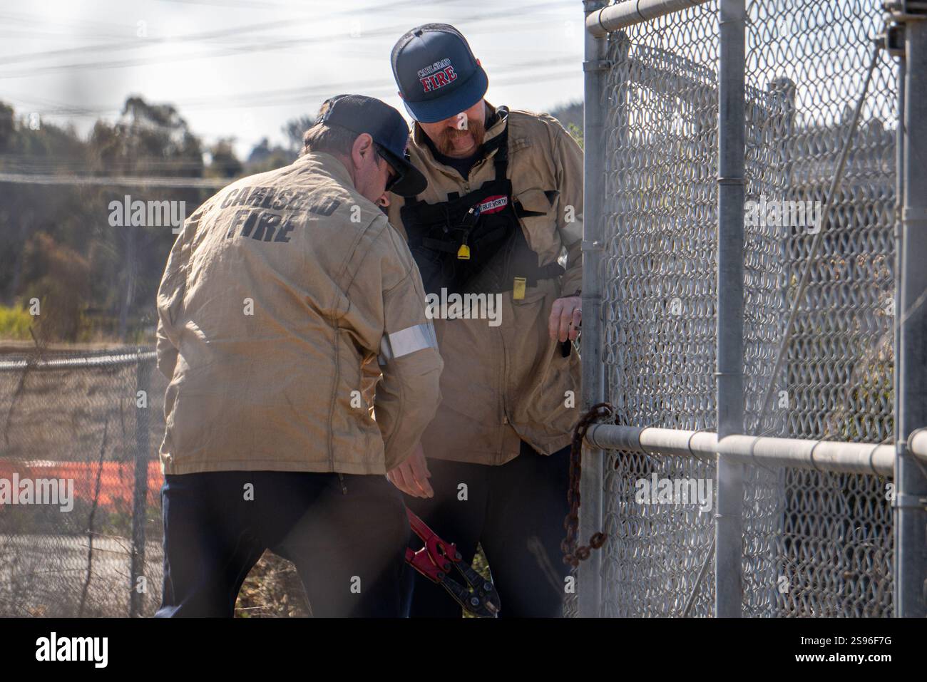 Firefighters with the Carlsbad Fire Department use bolt cutters to gain ...