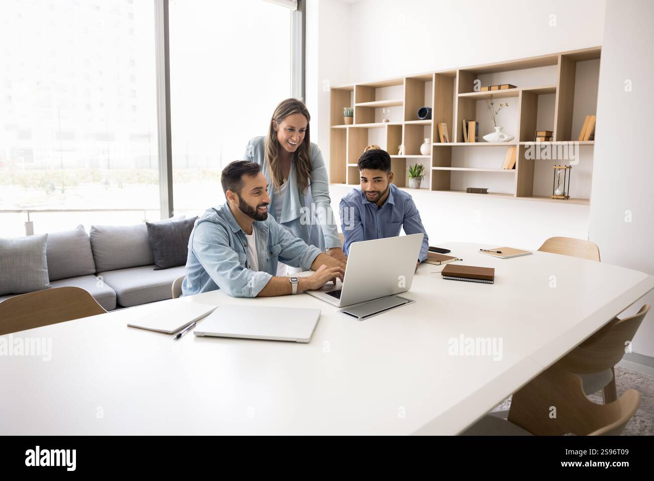 In modern conference room teammates engaged in workflow using laptop ...