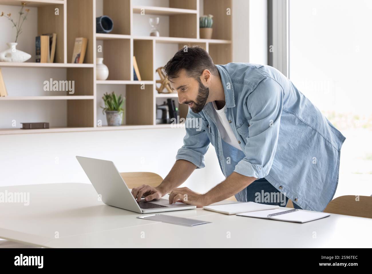 Businessman standing leaned at workplace desk working on laptop Stock ...