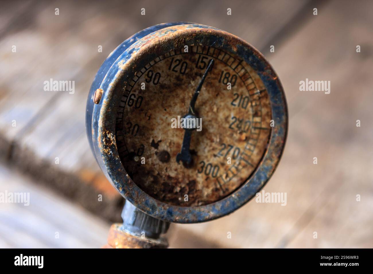 A rusted old pressure gauge with a black face and a white background ...