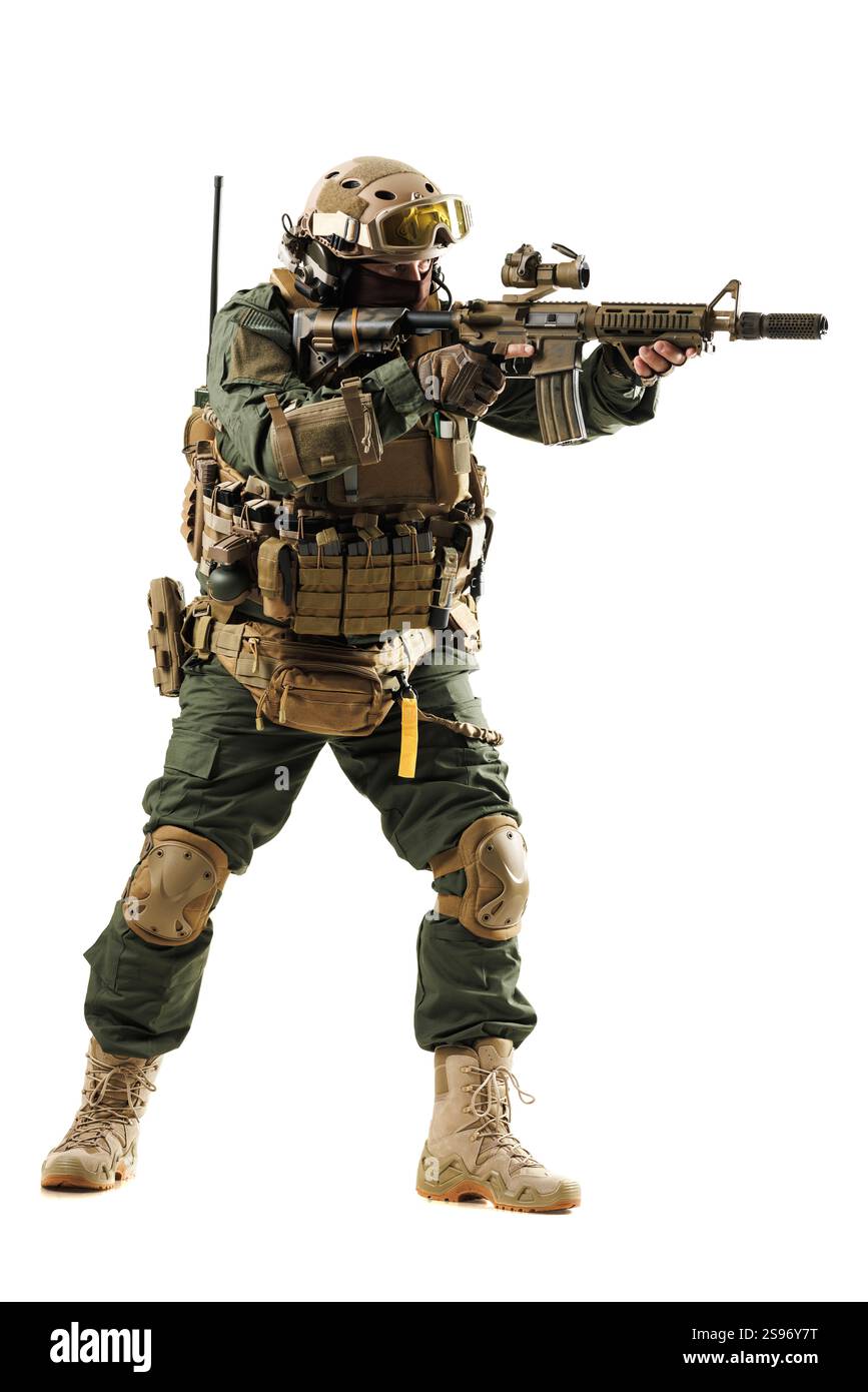 A soldier clad in military tactical gear aiming and poised in action ...