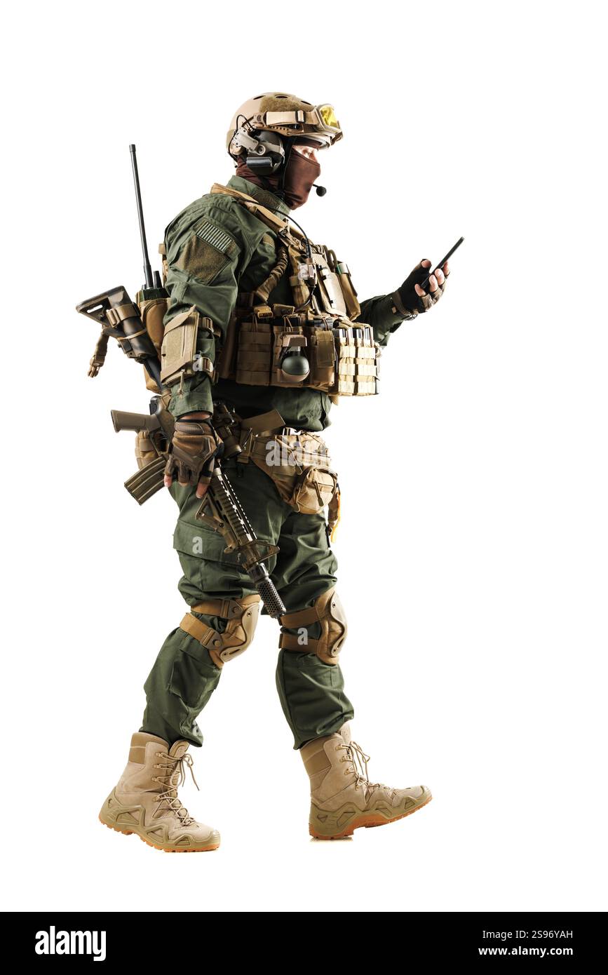 A soldier in green tactical gear, carrying military equipment, holds a ...