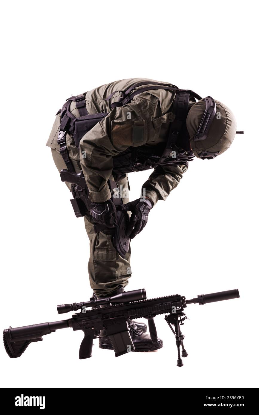 A special forces soldier in full tactical gear adjusts accessories ...