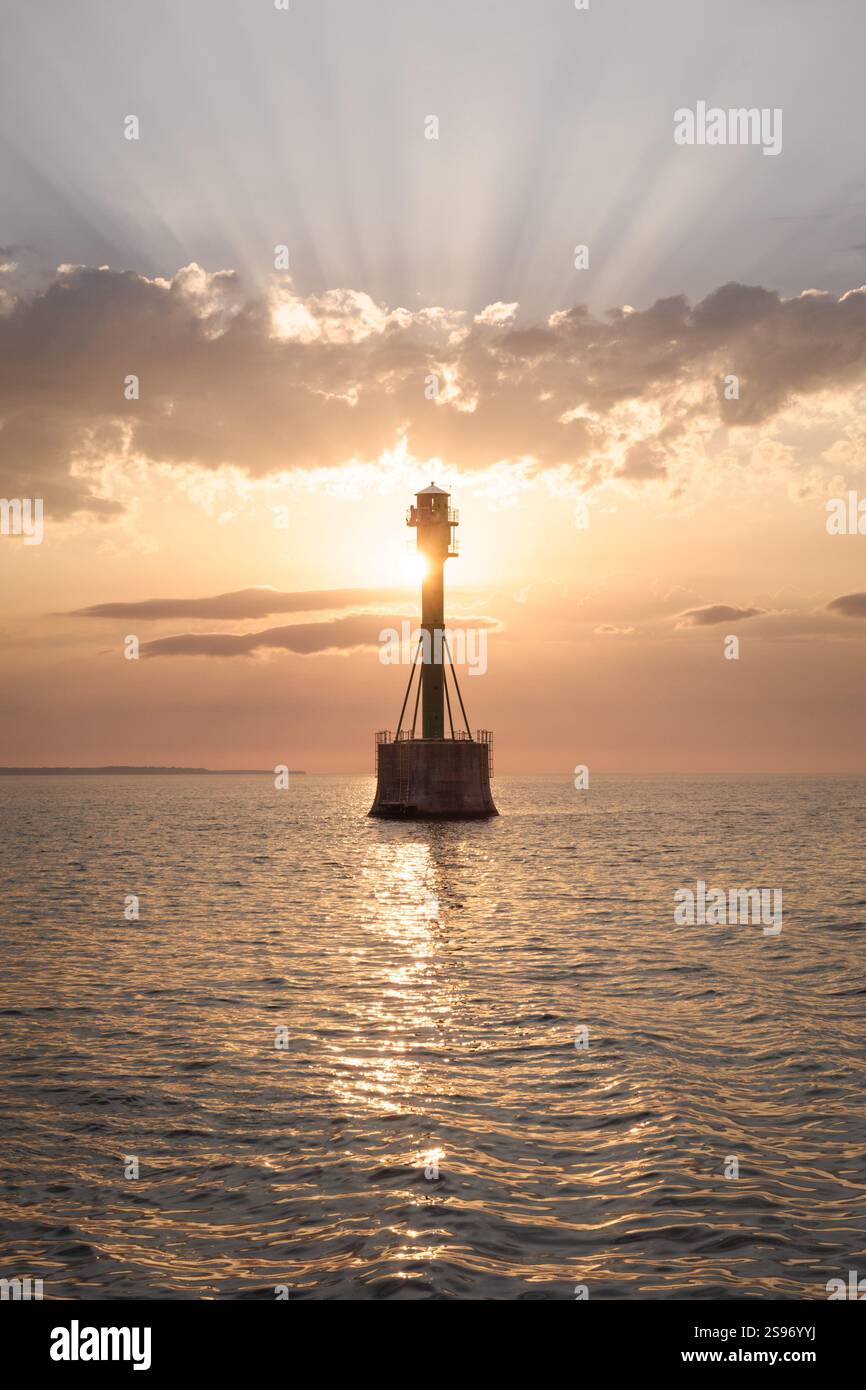 Lighthouse in the Ocean at Sunset with Sun Rays Stock Photo - Alamy