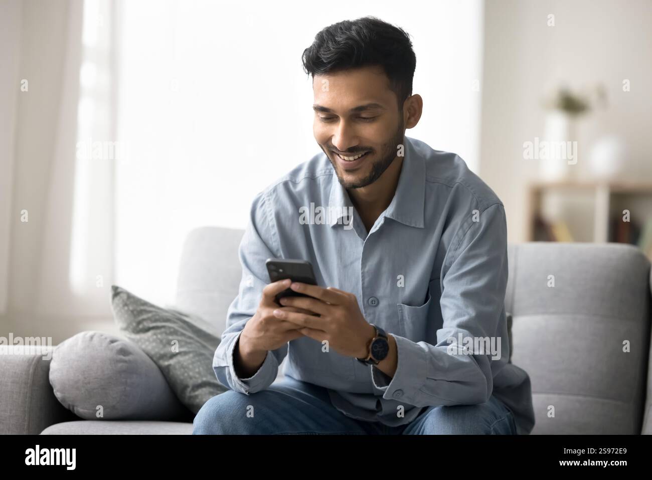 Smiling confident millennial man relax at living room use cellphone Stock Photo - Alamy