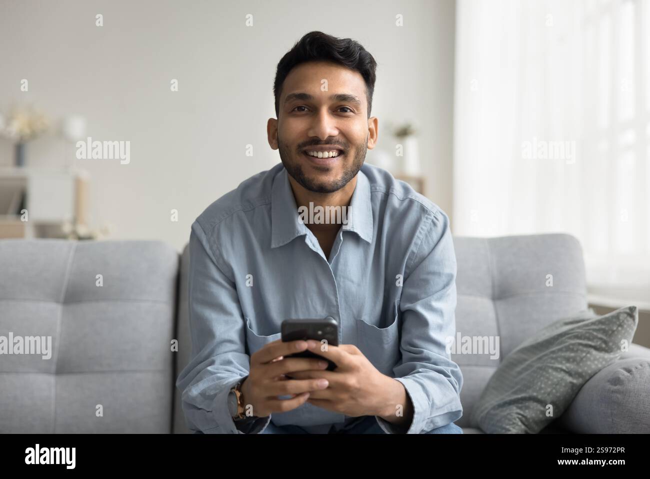 Young man hold cell look at camera with happy smile Stock Photo - Alamy