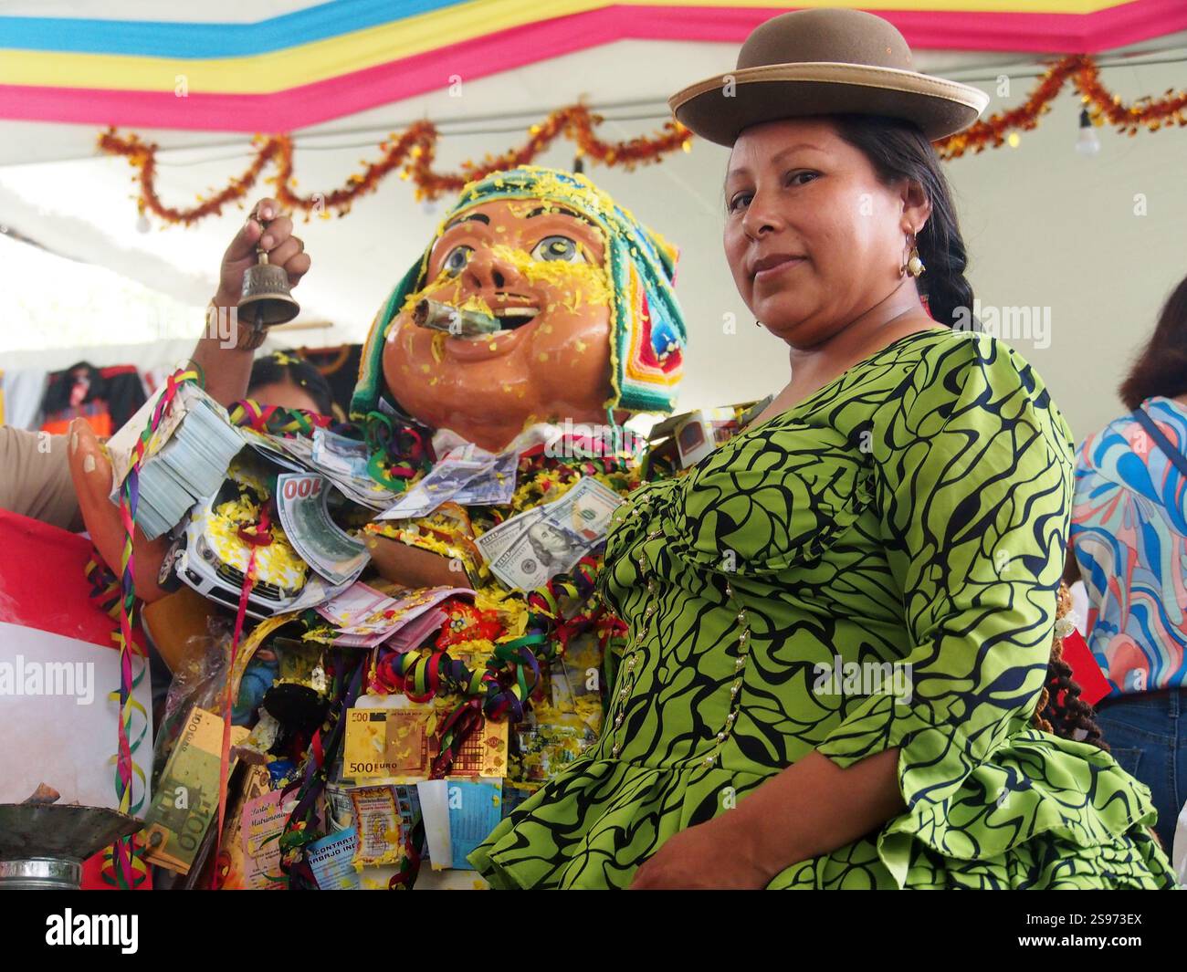Andean woman poses next to a life-sized Ekeko loaded with money and ...