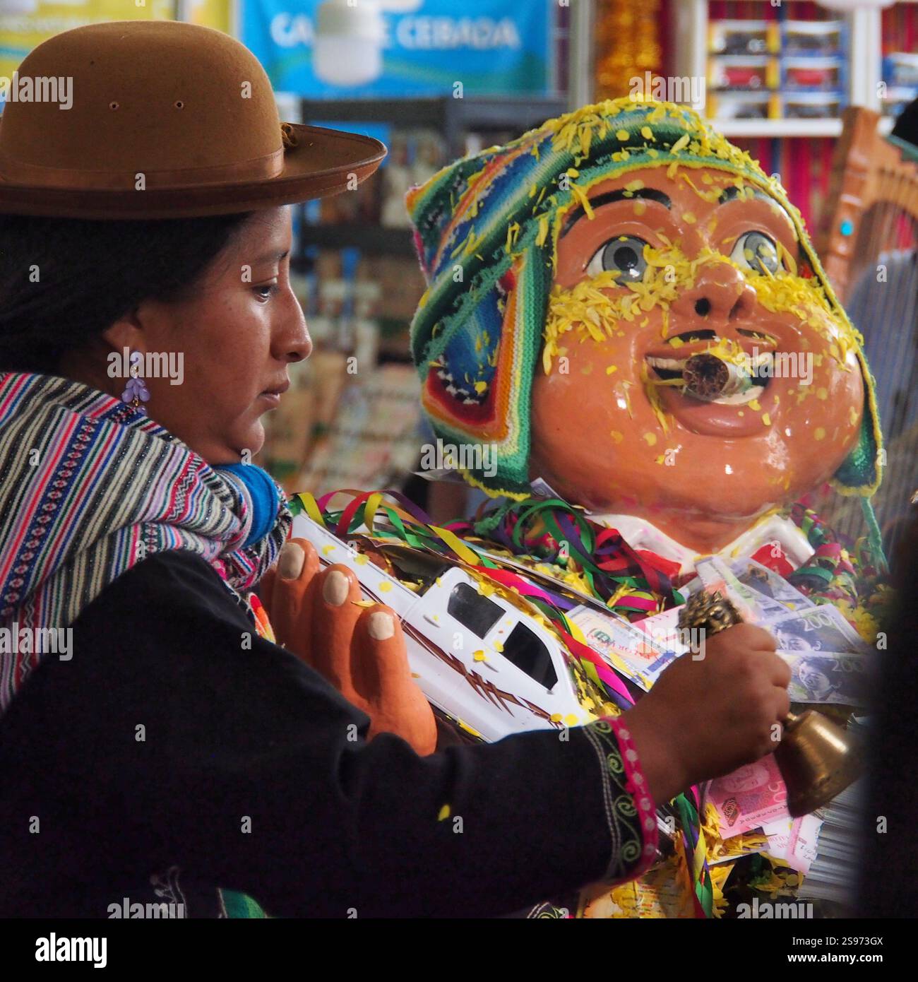 Indigenous woman ringing a ritual bell next to a life-size Ekeko when ...