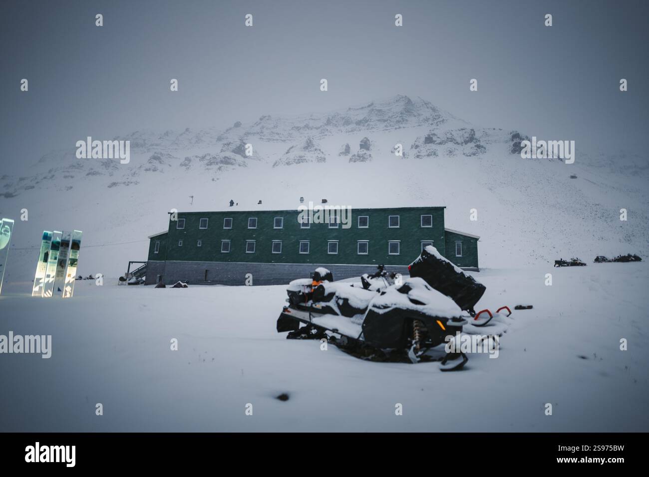 Snowmobile in front of green building under mountain in Longyearbyen ...