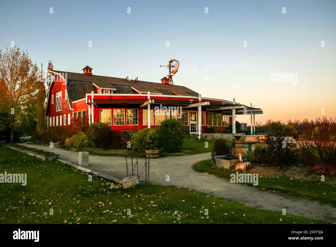 A red barn with a white roof and a clock tower. The barn is surrounded ...