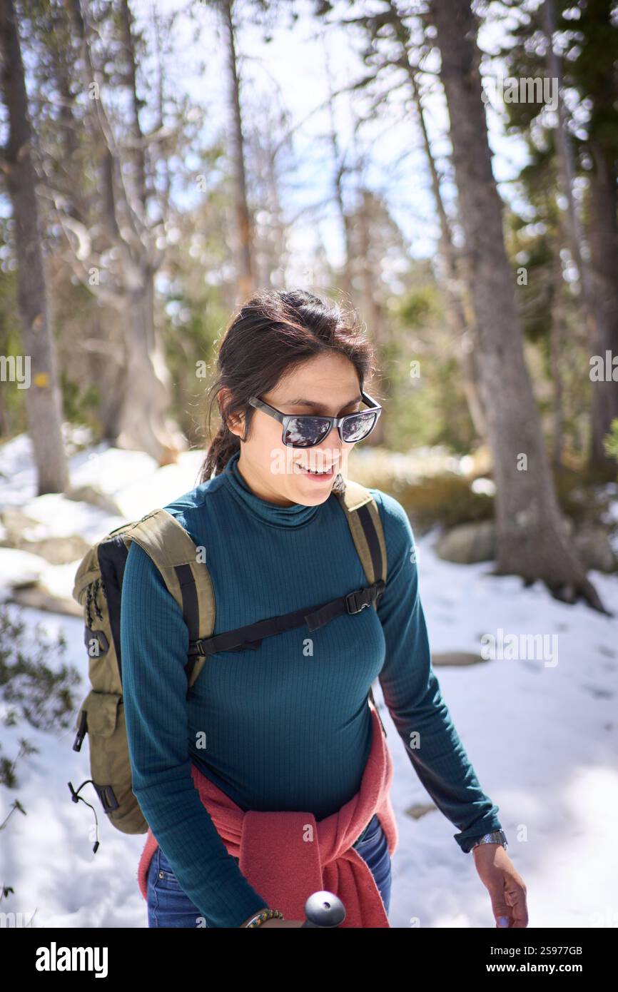 Hiker walking in snowy mountain forest trail with backpack and trekking ...