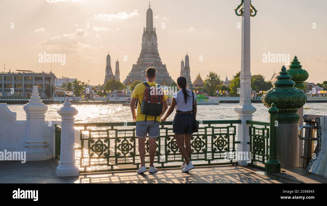 A couple stands hand in hand on a riverside promenade in Bangkok. They ...