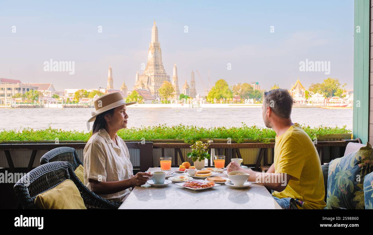 A tranquil breakfast setting on the river in Bangkok, where a couple ...