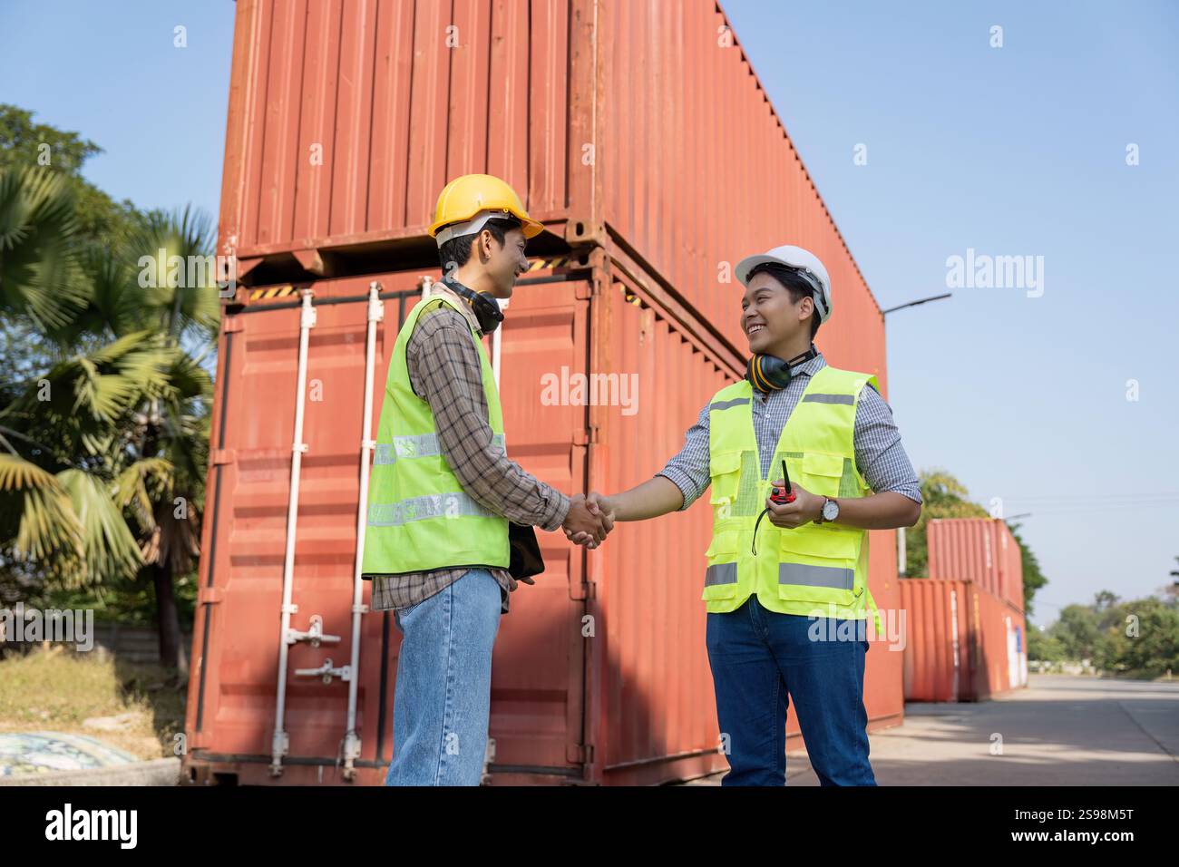 Engineers shaking hands in logistics and container management for import and export Stock Photo ...