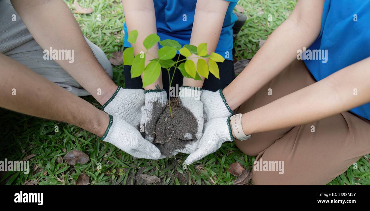 Family volunteers planting trees together for environmental ...