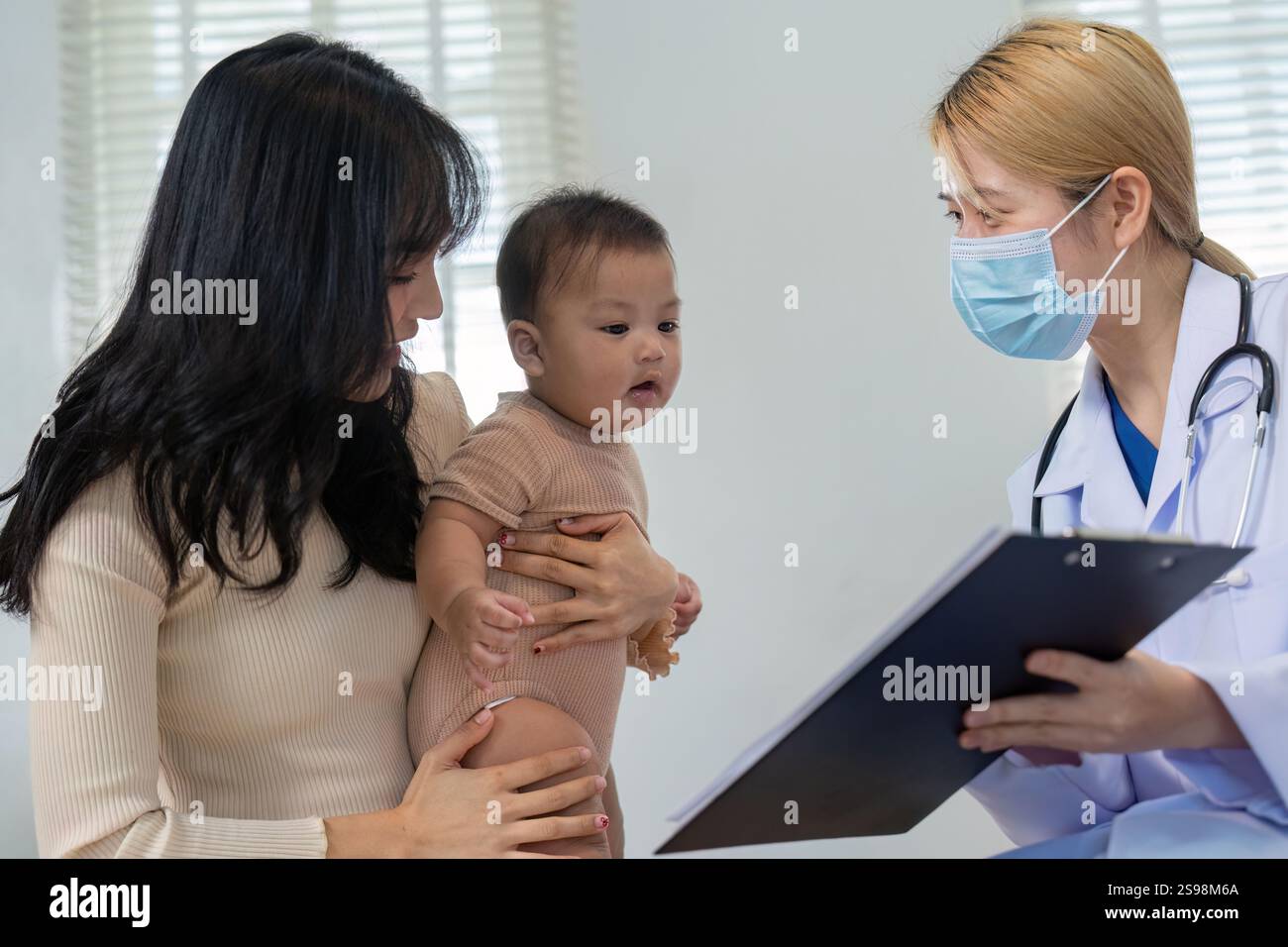 Pediatric consultation with doctor, parent, and baby in a medical setting Stock Photo - Alamy