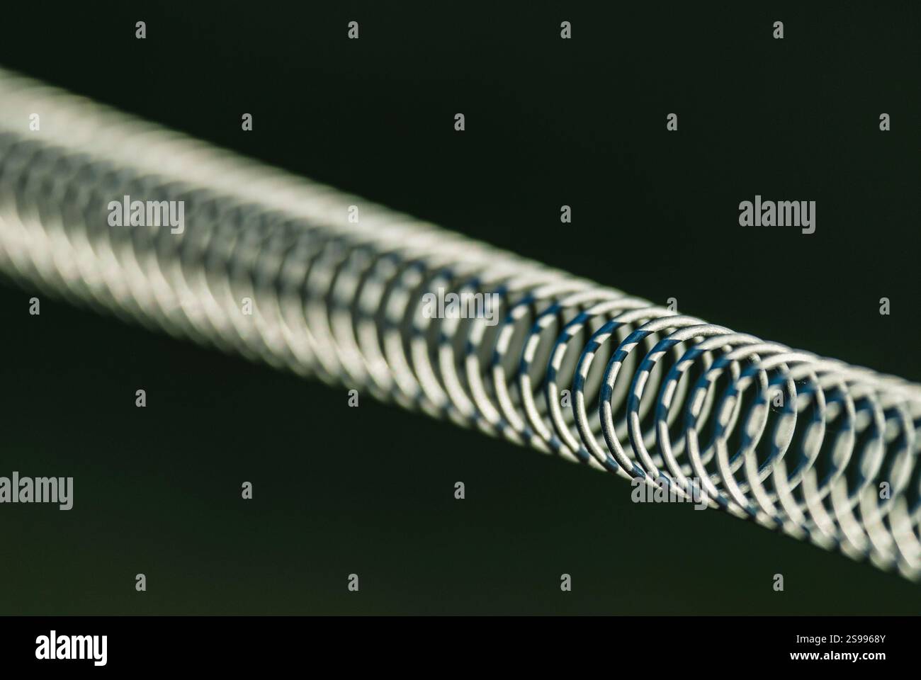 A spiral metal coil stretches horizontally, revealing its detailed ...
