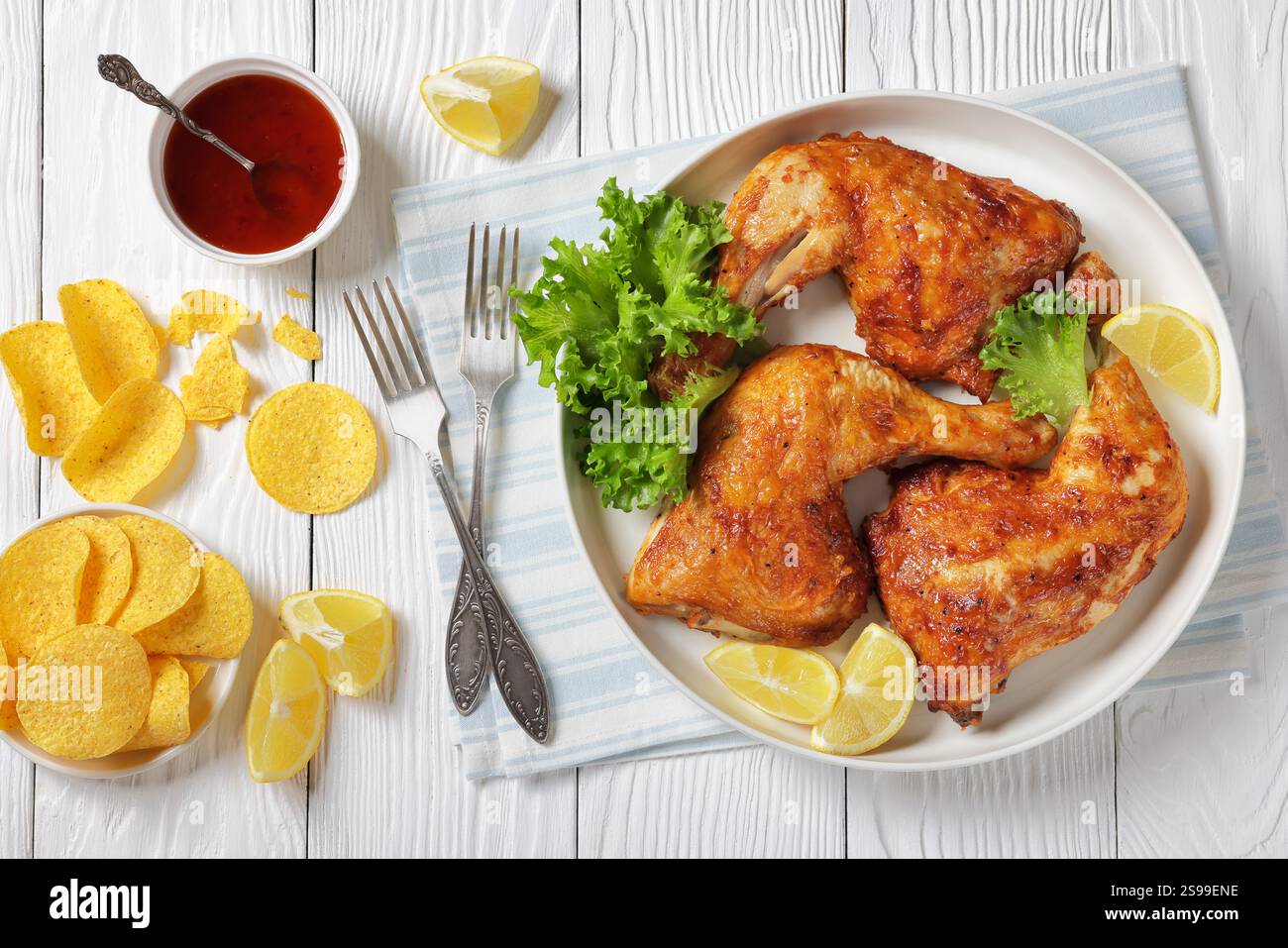 baked in oven three chicken leg quarters on white dish on white wooden table with forks, round ...