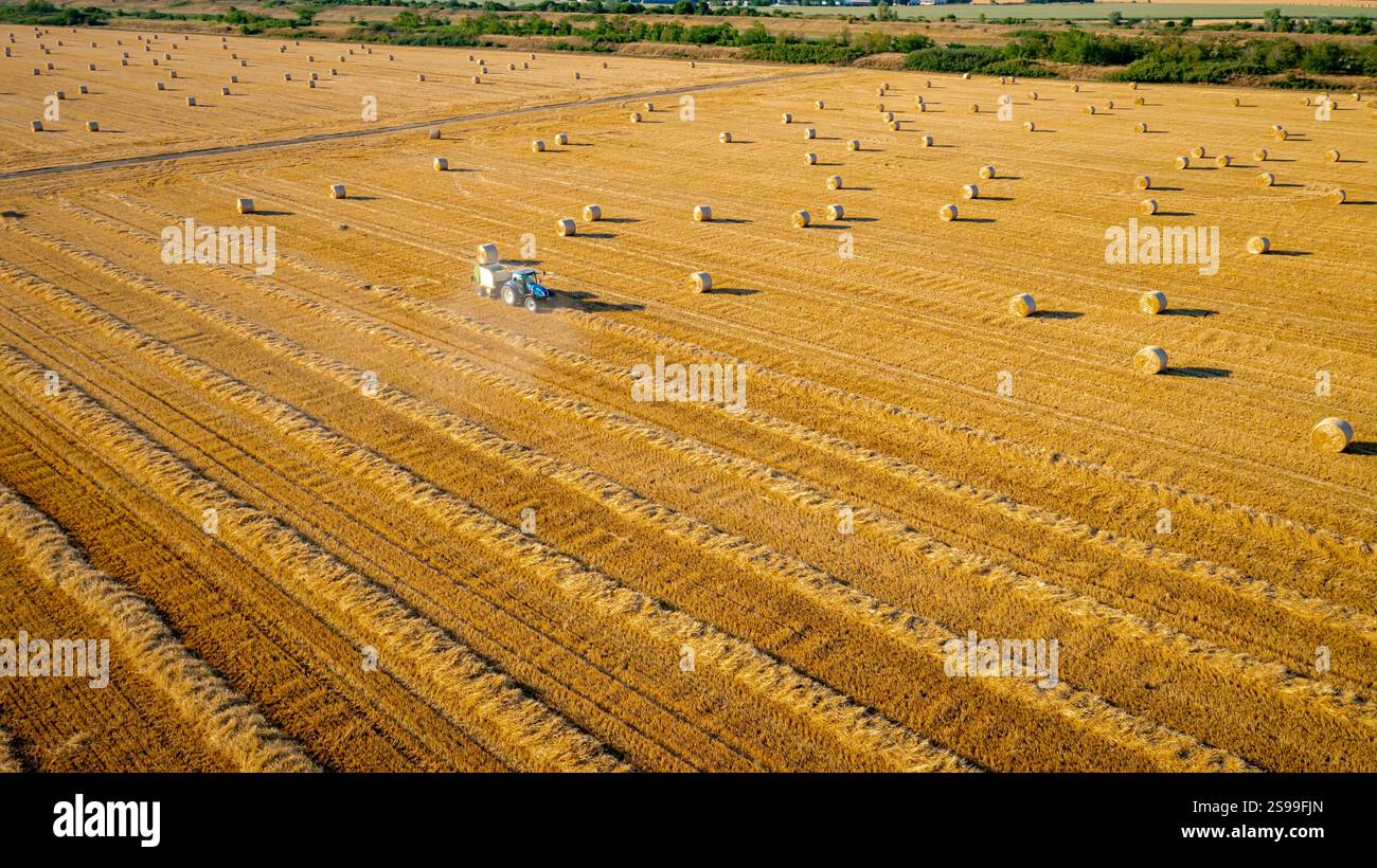 Above view on tractor as pulling round baler, machine that rolls up the ...