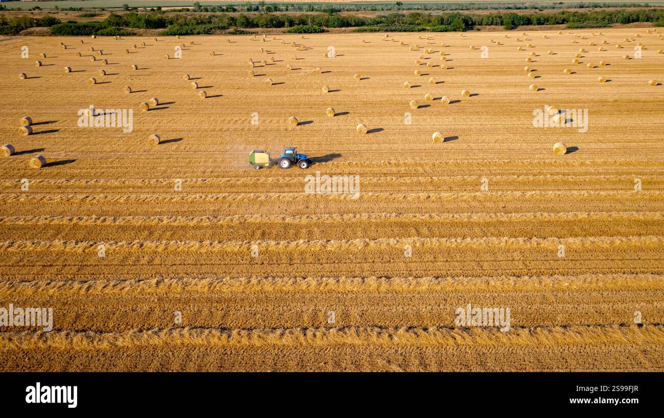 Above view sideways on tractor as pulling round baler, machine that ...