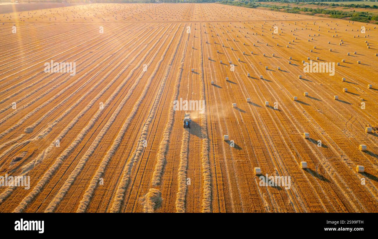 Above view with backlight on tractor as pulling round baler, machine ...