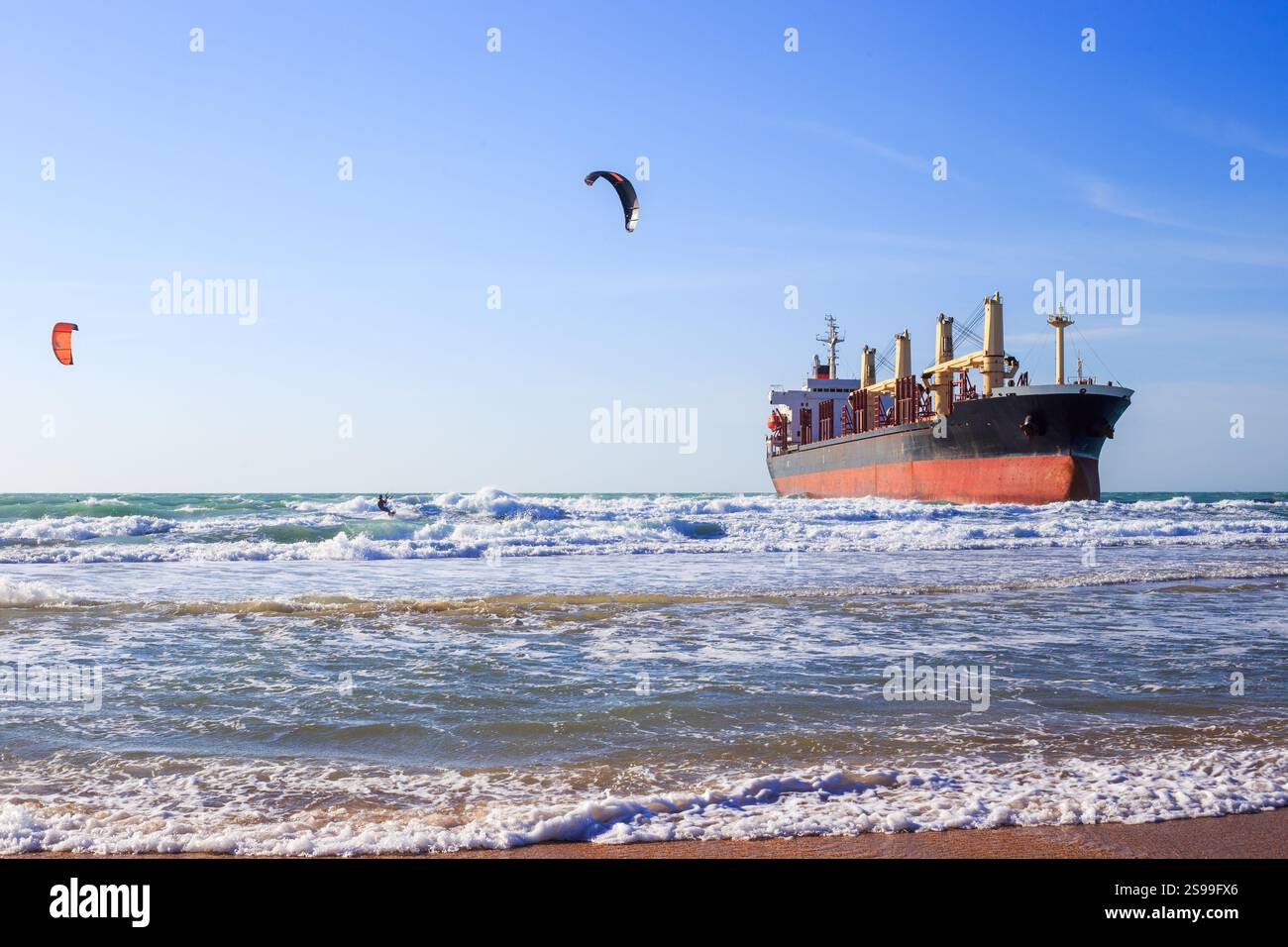 A large cargo ship on the Black Sea coast, kitesurfers on boards with a ...