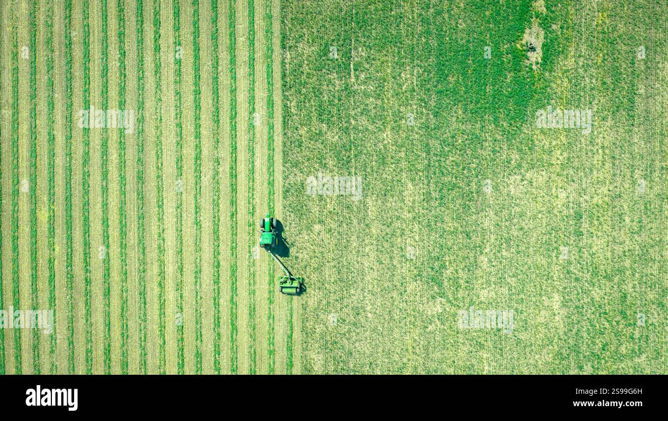 Above top view, tractor is pulling grass cutting machine over field ...