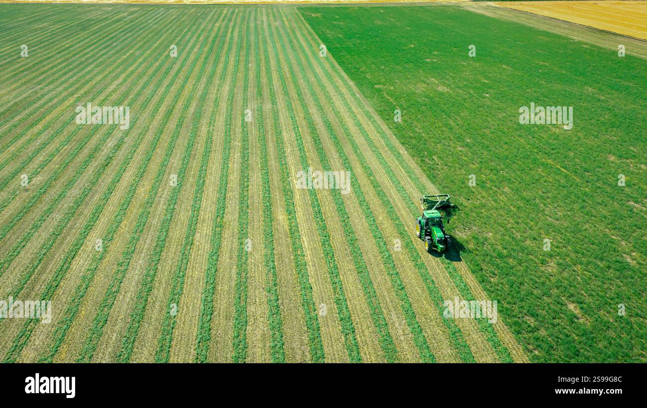Above view, tractor is pulling grass cutting machine over field with ...