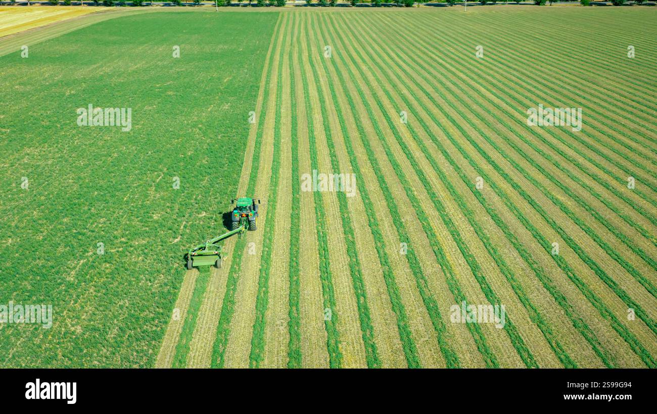 Above view, tractor is pulling grass cutting machine over field with ...