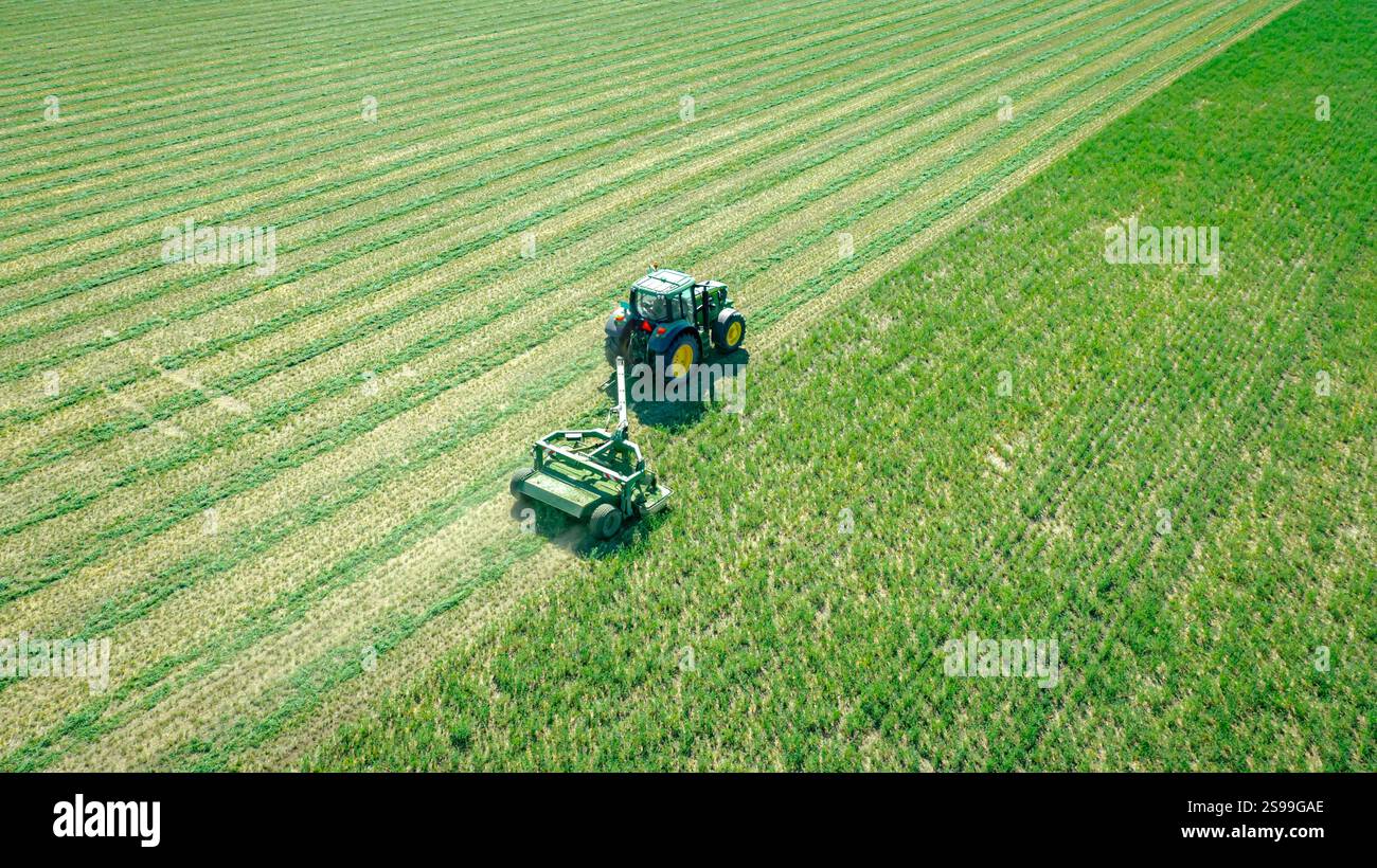 Above view, tractor is pulling grass cutting machine over field with ...