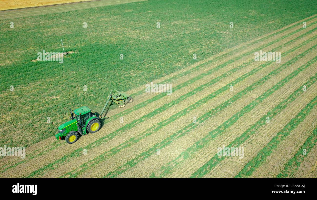 Above view, tractor is pulling grass cutting machine over field with ...
