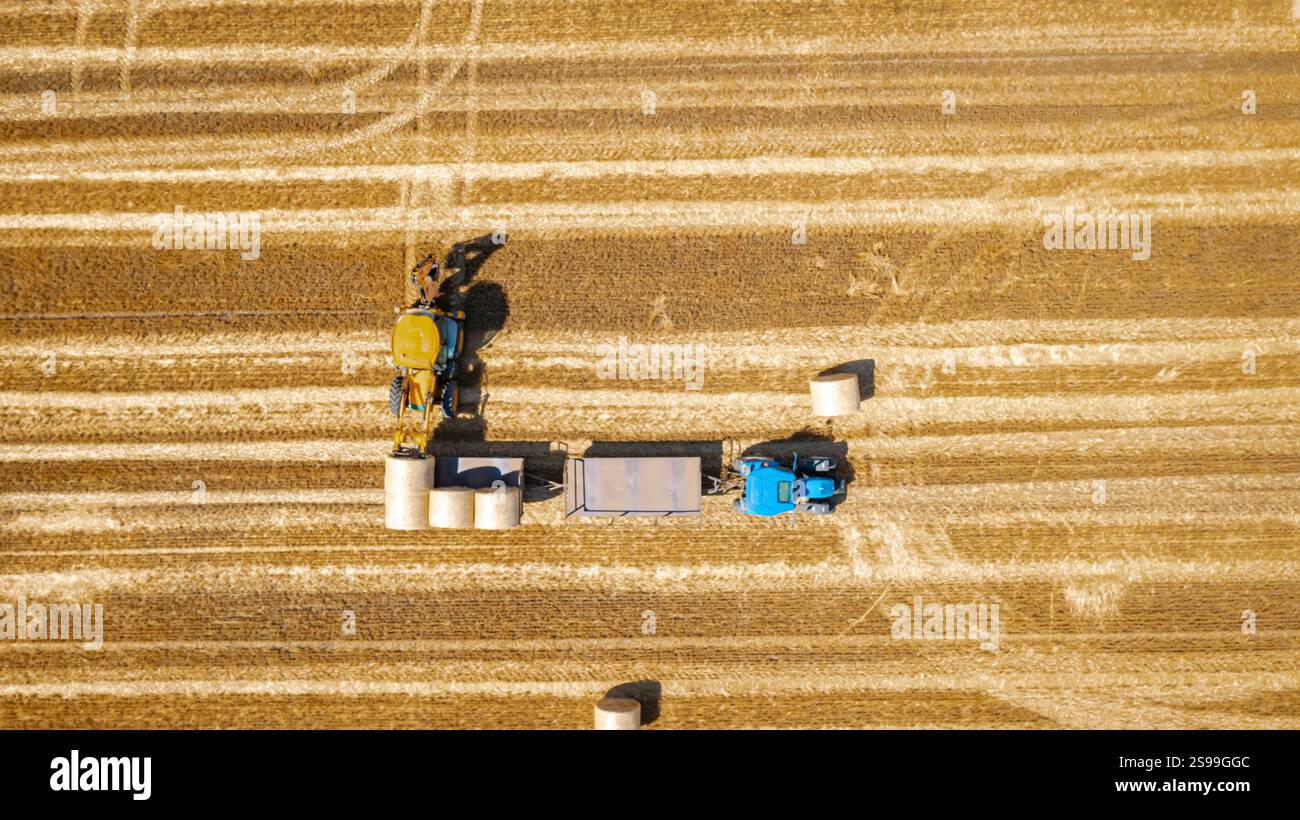 Above top view on excavator as loading straw bales on trailer, tow by ...