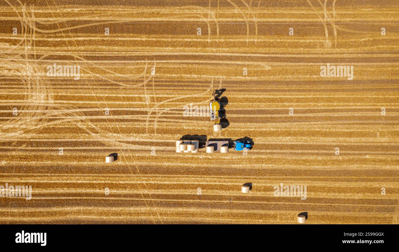 Above top view on excavator as loading straw bales on trailer, tow by ...