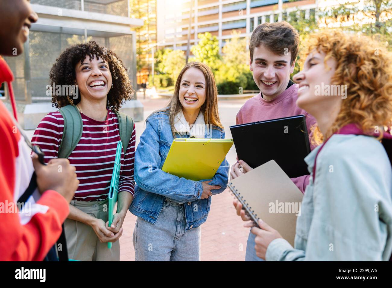 Diverse teenage students having fun talking together outdoors at ...