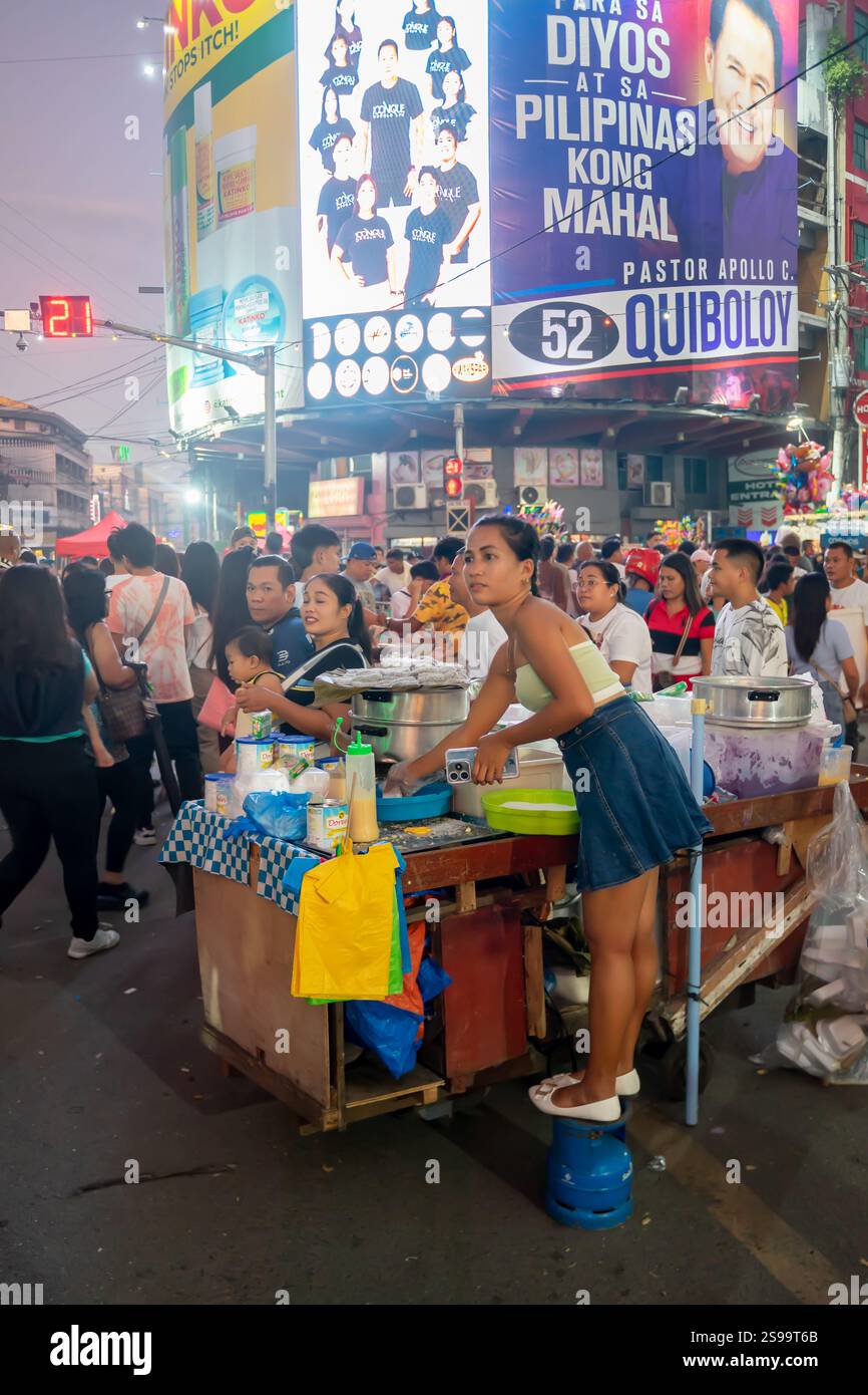 Young woman selling street food at food stall at night market Colon ...