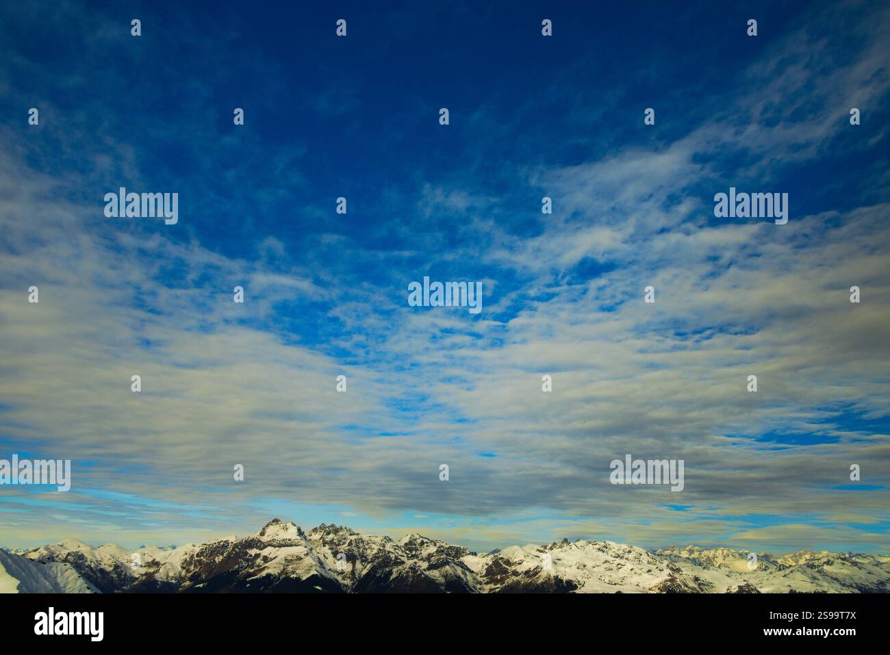 Mountain landscape. Snow-capped peaks against the blue sky with clouds ...