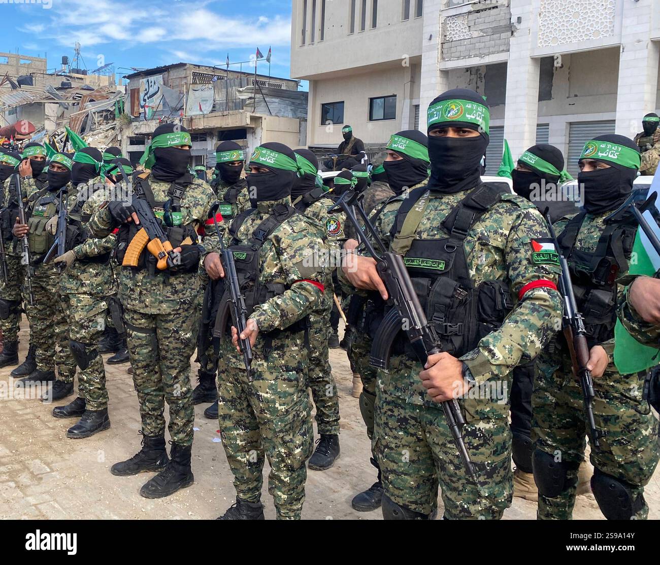 Hamas fighters secure an area in a square before handing over four ...