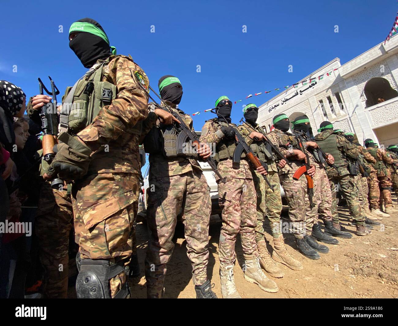Hamas fighters secure an area in a square before handing over four ...