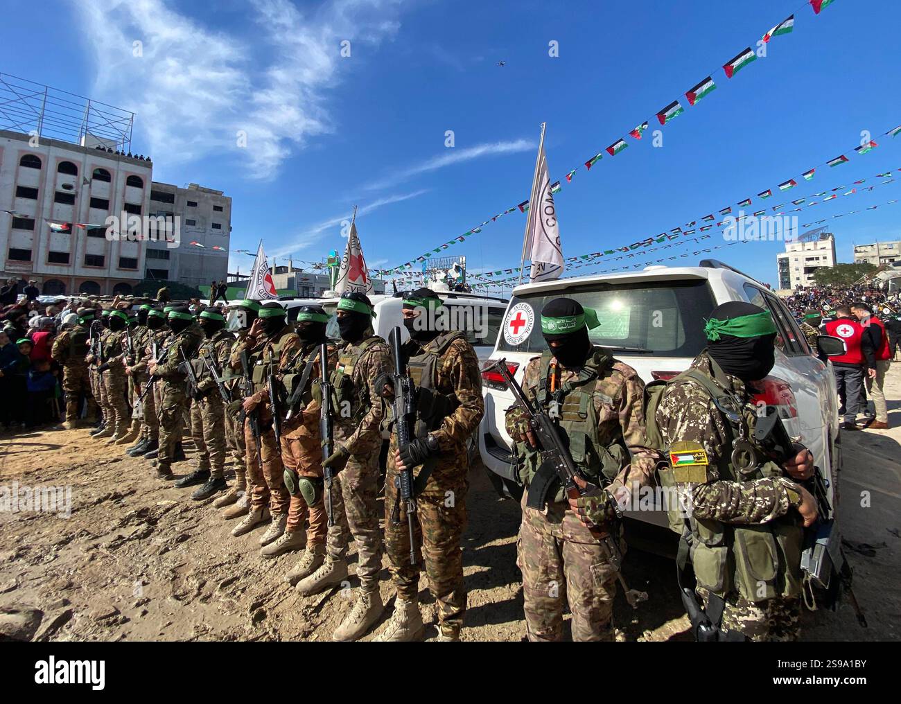 Hamas fighters secure an area in a square before handing over four ...