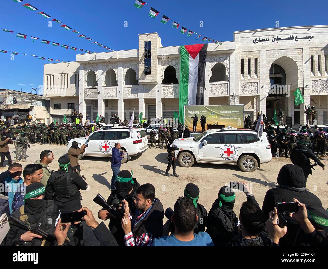 Hamas fighters secure an area in a square before handing over four ...