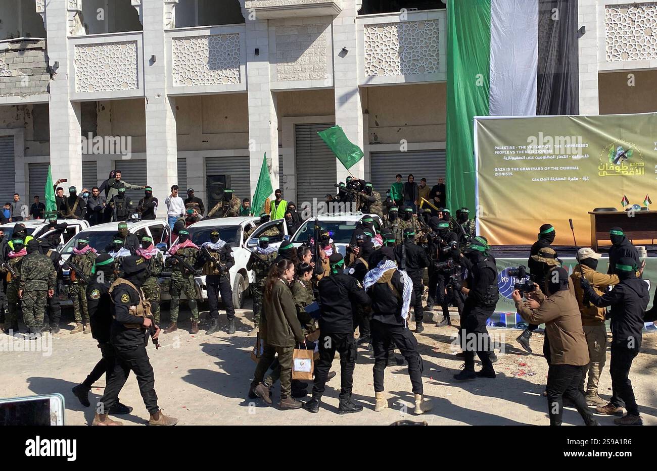 Hamas fighters secure an area in a square before handing over four ...