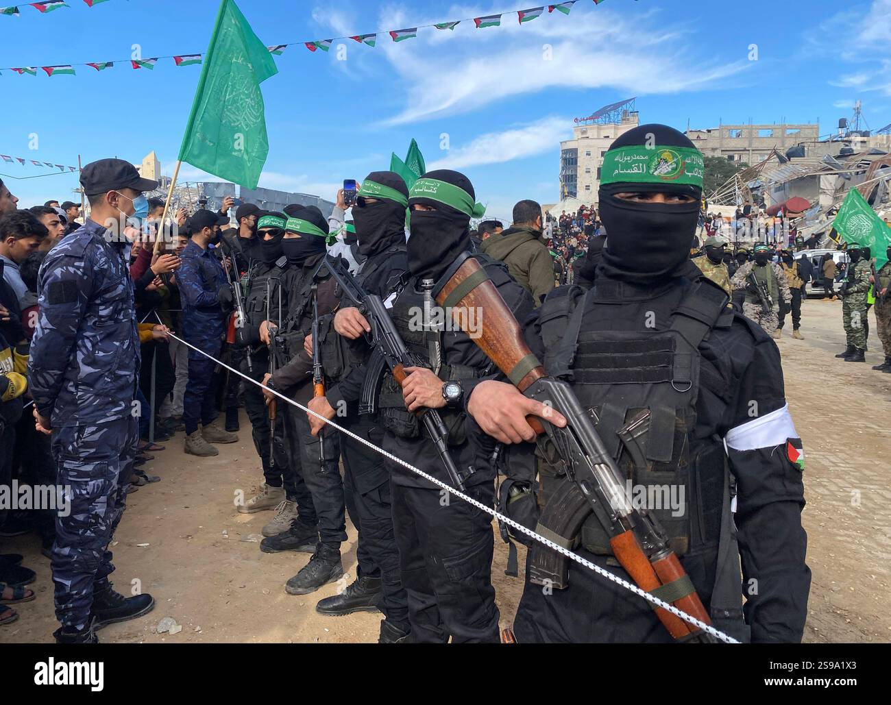 Hamas fighters secure an area in a square before handing over four ...