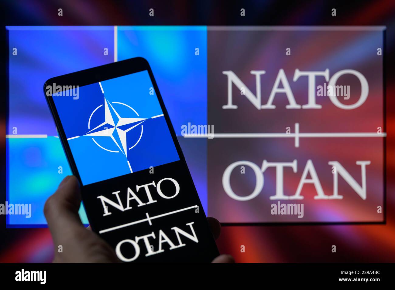The NATO - OTAN logo is being displayed on a mobile phone with the NATO ...