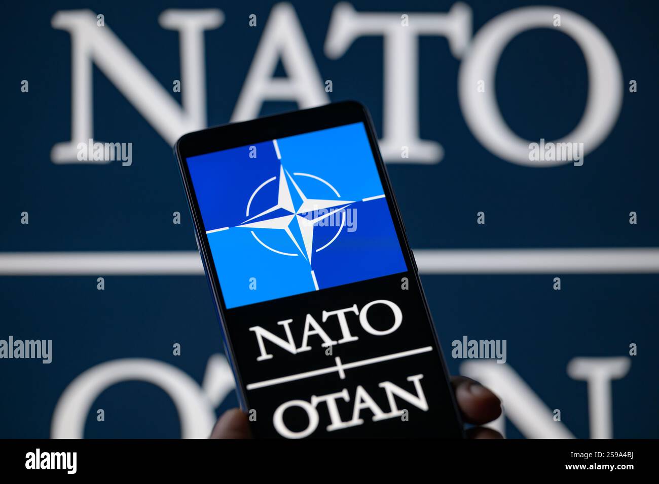The NATO - OTAN logo is being displayed on a mobile phone with the NATO ...